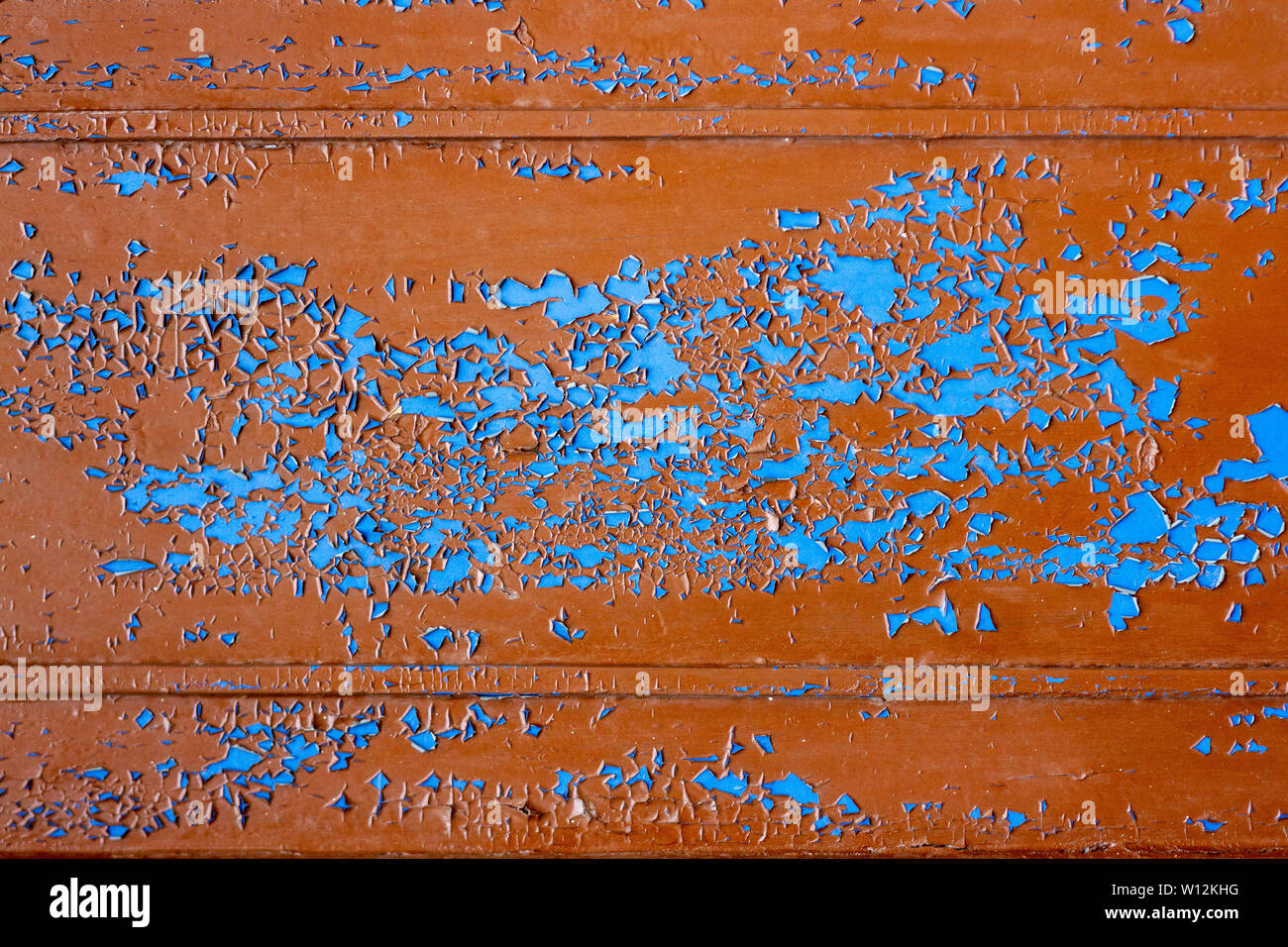 A layer of cracked brown paint showing the older blue paint underneath ...