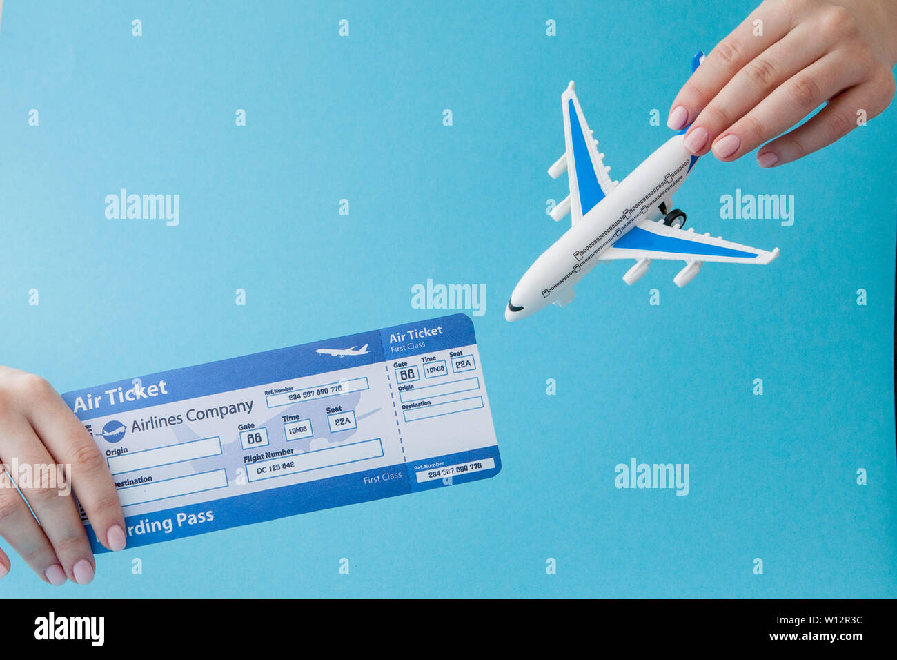 Plane and air ticket in woman hand on a blue background. Travel concept ...
