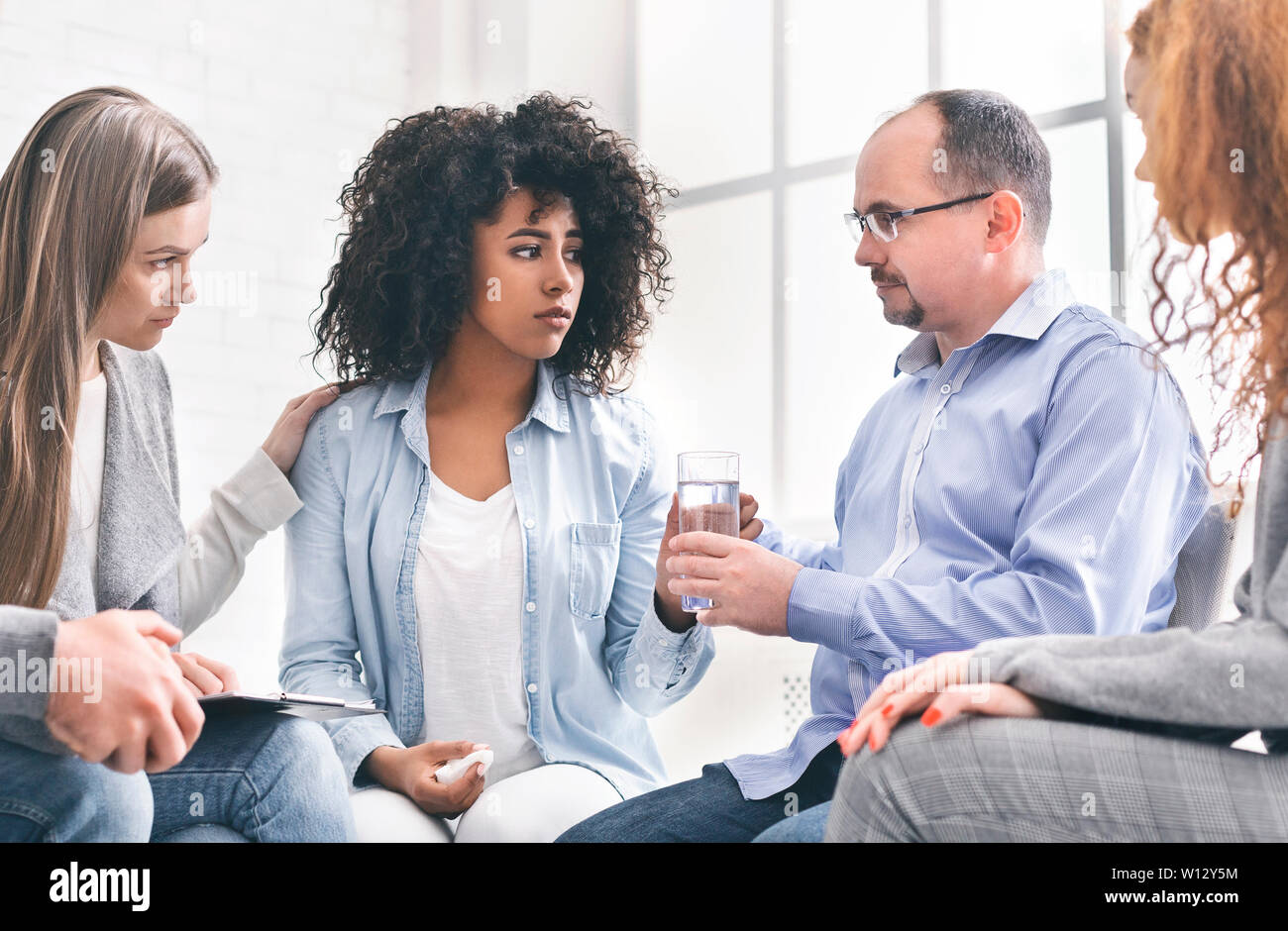 Kind people comforting african woman at support group Stock Photo - Alamy