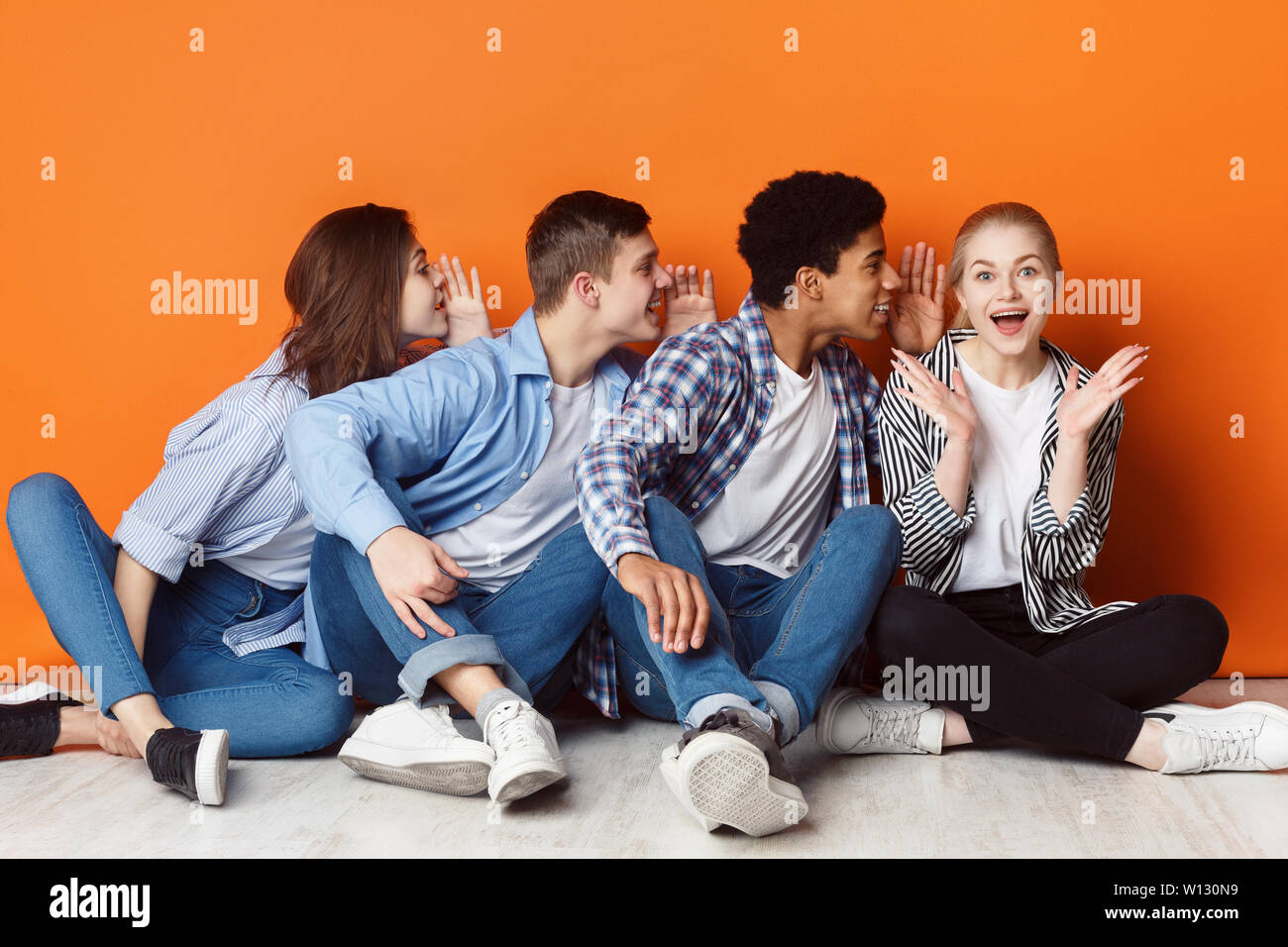 Group of friends whispering each other in the ear Stock Photo - Alamy