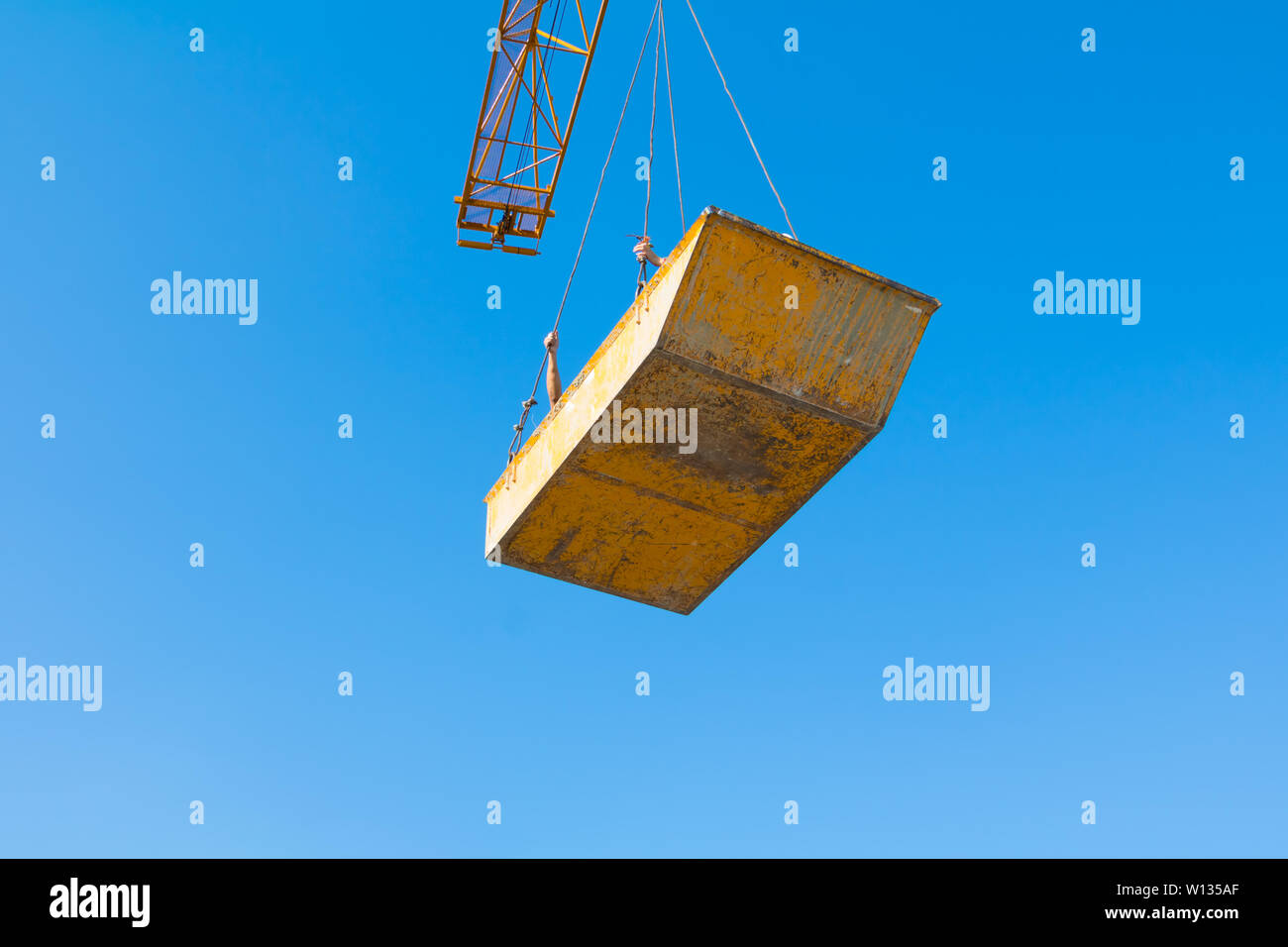 Tower crane bucket of yellow in building construction site. blue sky ...