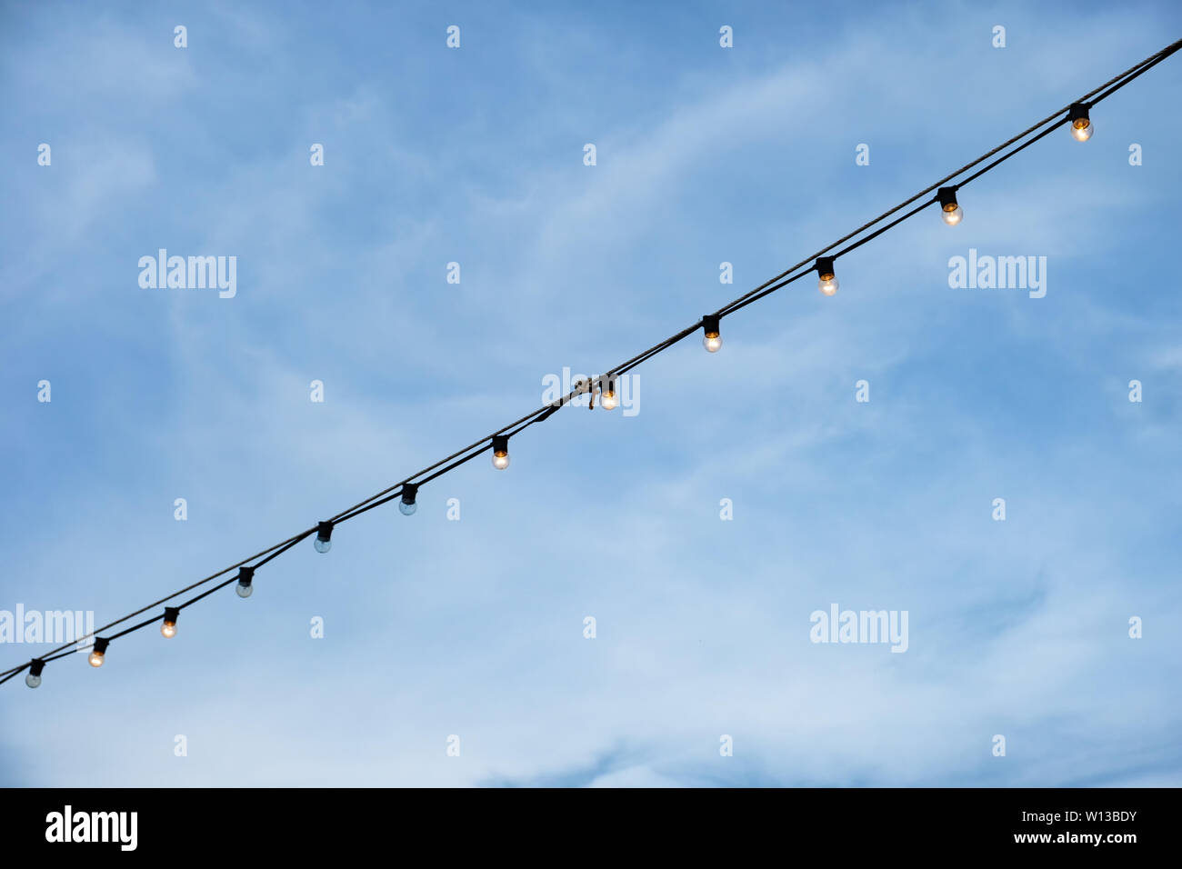 Electric wire dim hanging on blue sky for party Stock Photo - Alamy