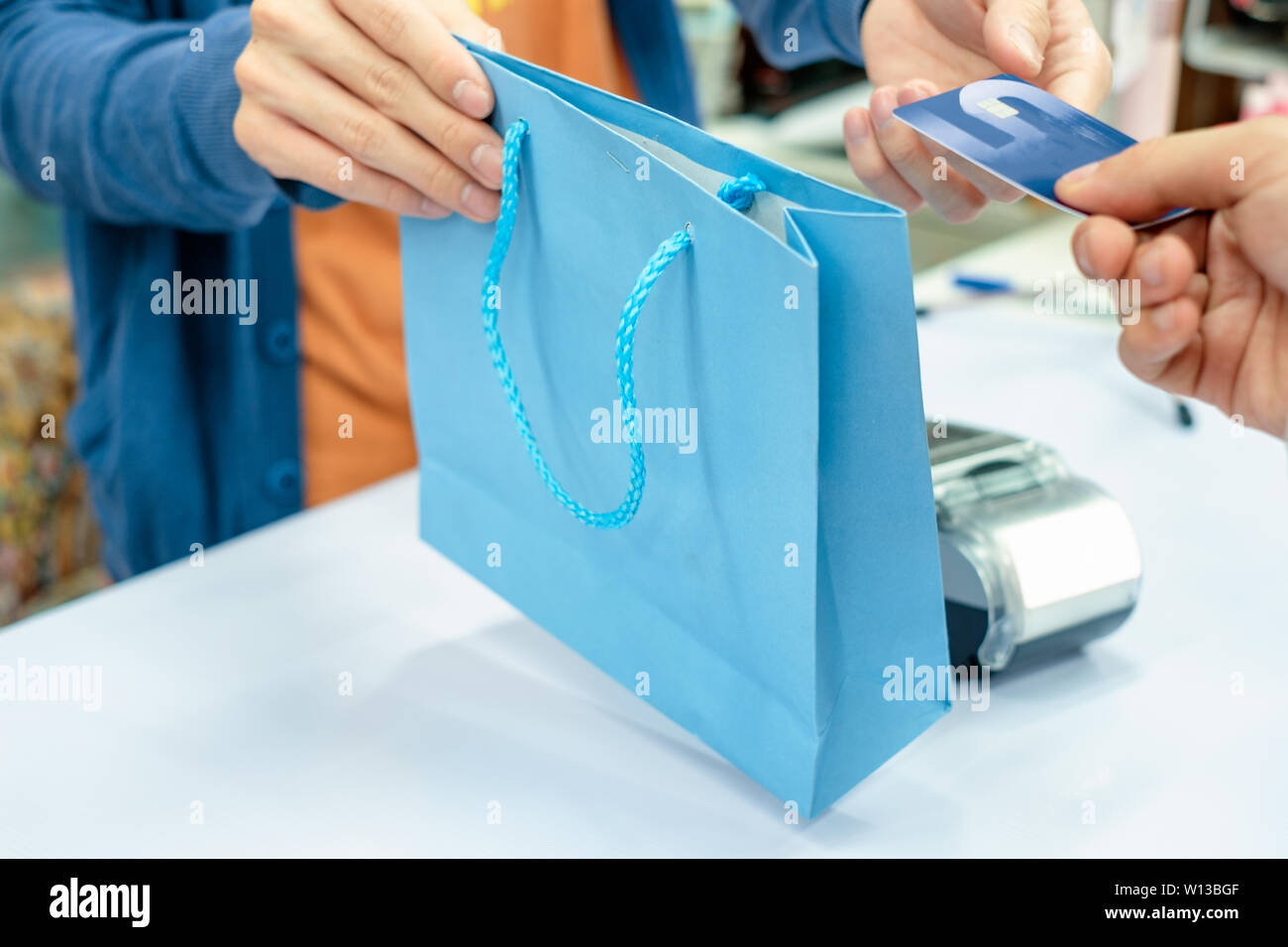 Hand giving credit card and take paper bag from staff cashier in ...