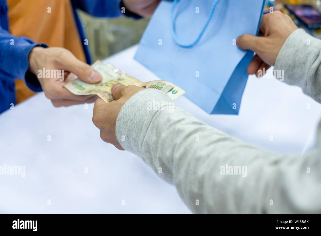 Hand giving money and take paper bag from staff cashier in supermarket ...
