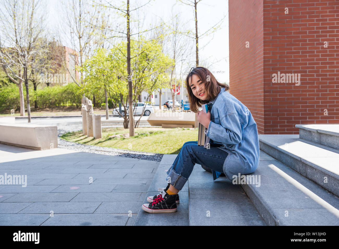 Beautiful female college student sitting on the campus ladder Stock ...