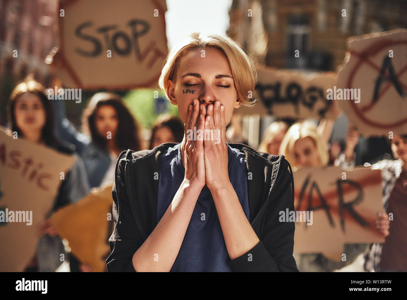 Stop war Young woman with word love written on her face keeping eyes ...