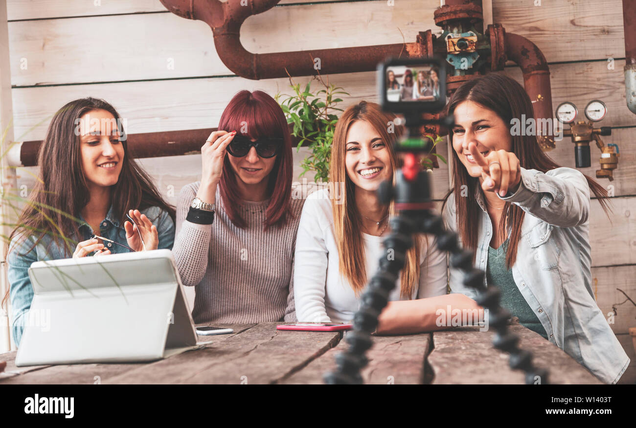 four young vloggers talking on the camera leaning against a small ...
