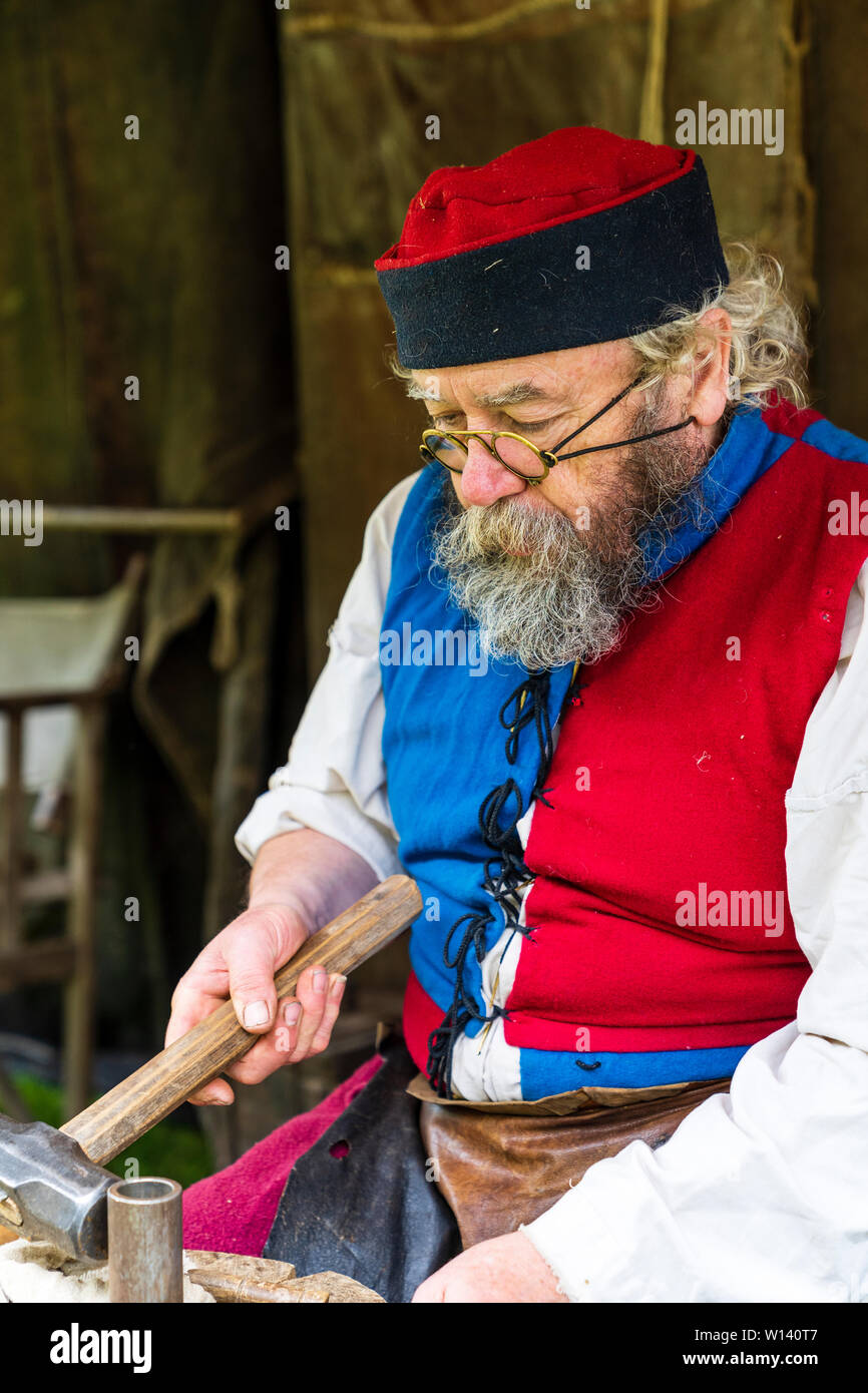 Medieval reenactment event. Senior man, metal worker, with bushy beard ...
