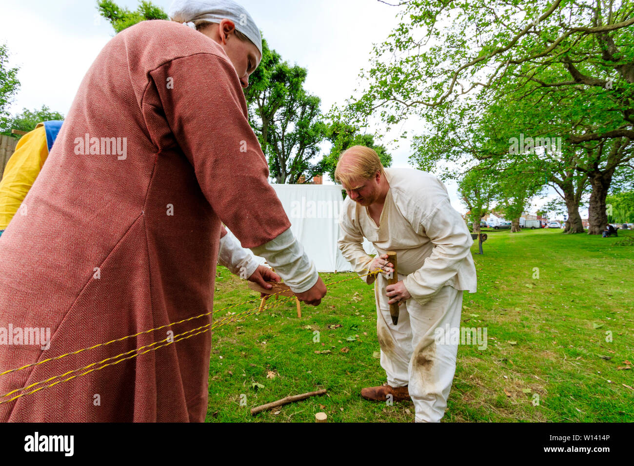 Living history medieval re-enactment. Rope maker, man twisting length ...