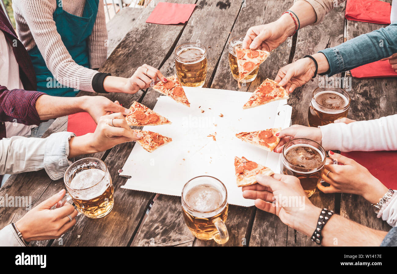 Happy friends eating take away pizza and drinking beer over a vintage ...