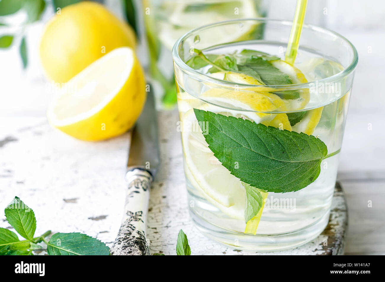 mojito cocktail in glass, lemons and mint leaves in bascet on white ...