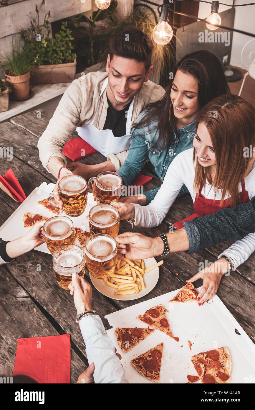 Happy group of friends drinking beer and eating pizza at brewery bar ...