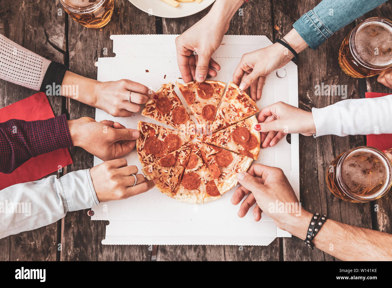 Happy friends eating take away pizza and drinking beer over a vintage ...