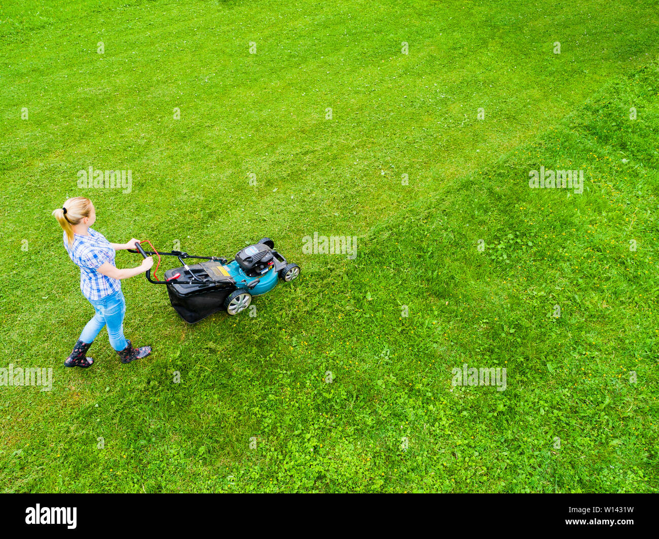Beautiful girl cuts the lawn. Mowing lawns. Aerial view beautiful woman ...
