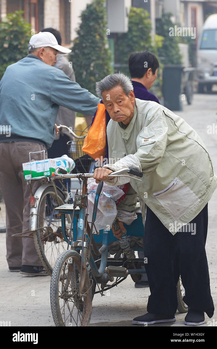 An Elderly Chinese Man Pushing His Cycle Rickshaw Through A Narrow ...