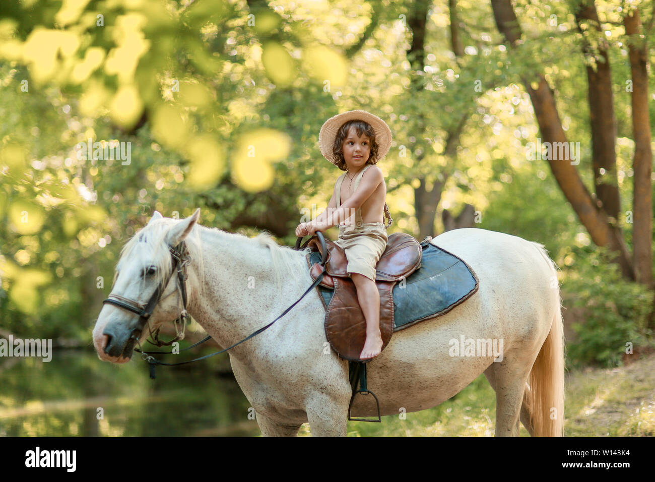 Little baby boy with curly hair dressed as hobbit playing with horse in ...