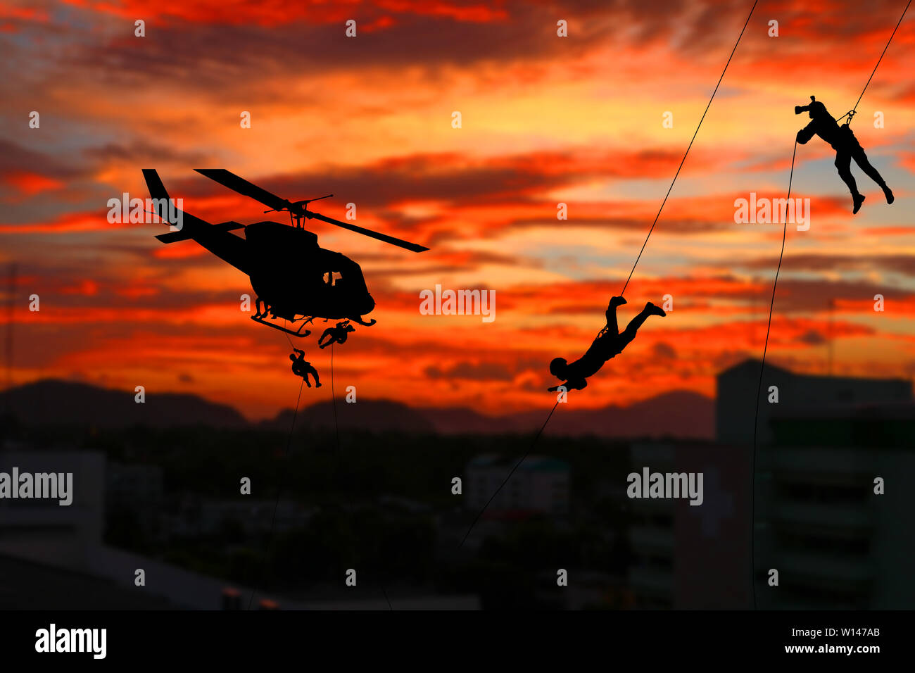 Silhouette Soldiers rappel down to attack from helicopter with sunset ...