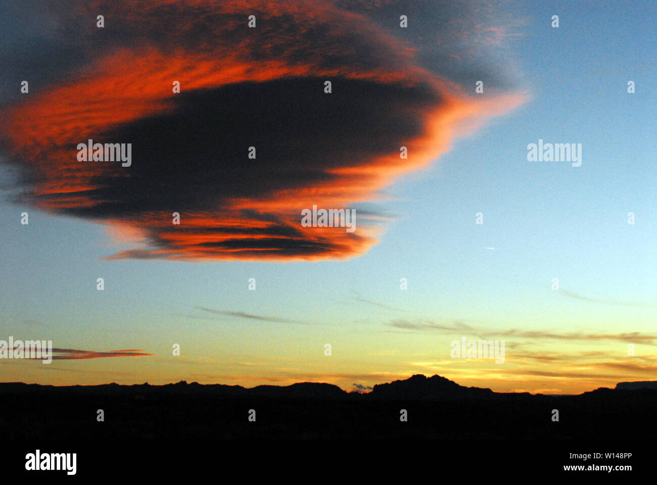 A gorgeous circular Lenticular cloud vividly reflects the sunset over ...
