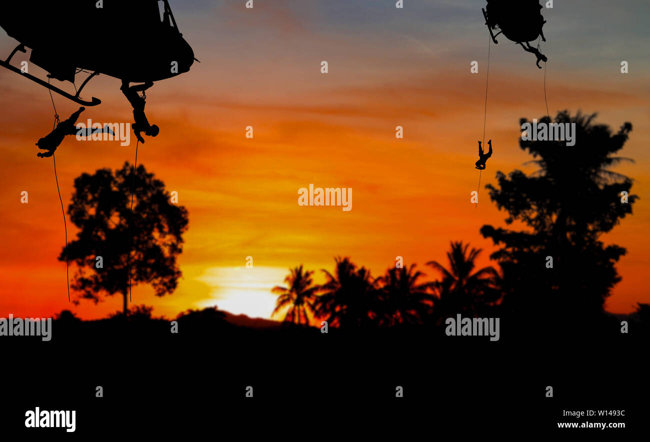 Silhouette Soldiers rappel down to attack from helicopter with sunset ...