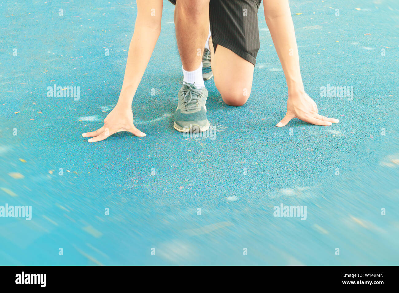 arm male touch floor start pose training running on track rubber blue ...
