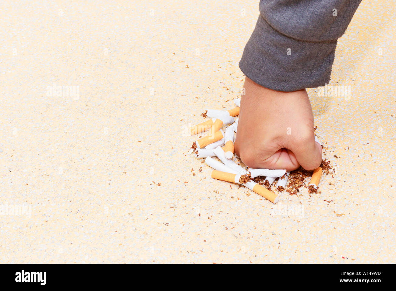 male hand crushed pile cigarettes Close up on table terrazzo flooring ...