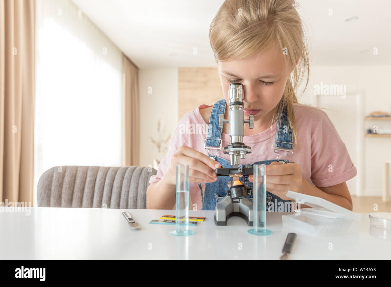 Girl with microscope at home learning chemistry and playing Stock Photo ...