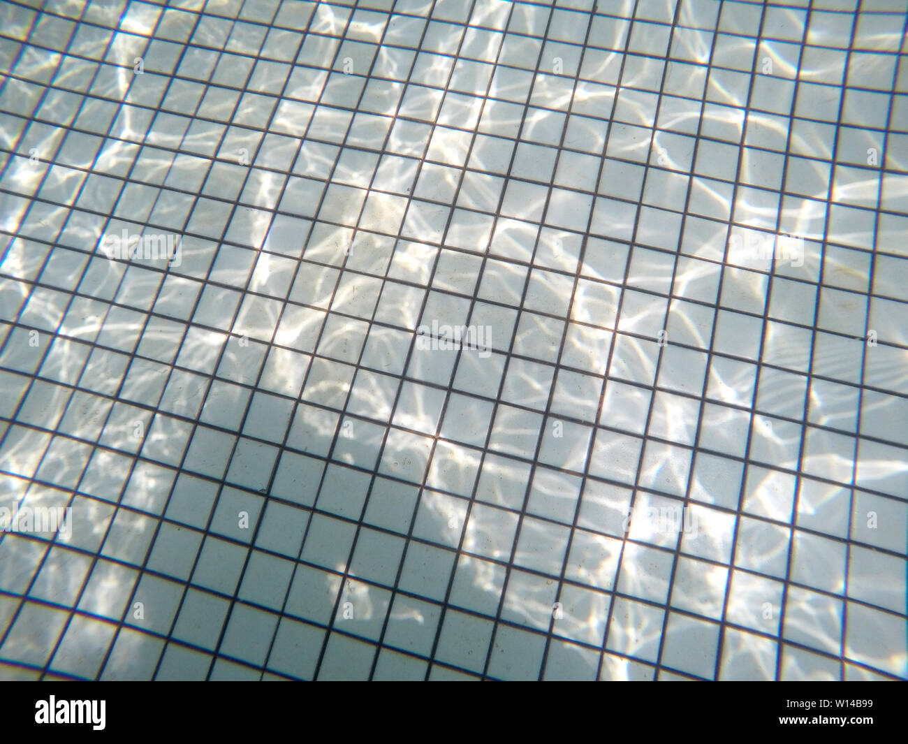 underwater view of swimming pool floor with sunlight reflections ...