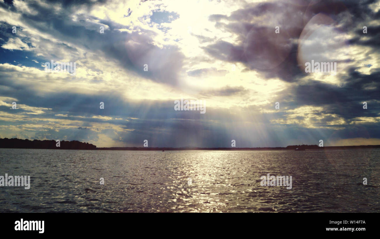 Orange Sun Rays Through Clouds Morning Sunrise on water Stock Photo - Alamy
