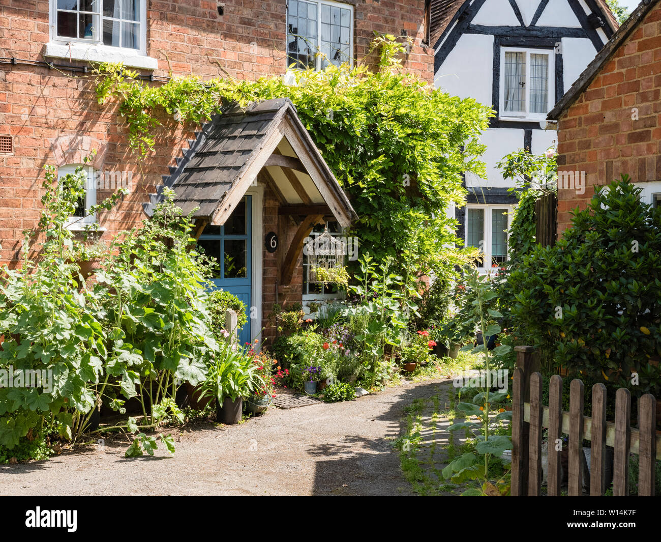 An old fashioned cottage in the sun with a porch roof and pretty ...