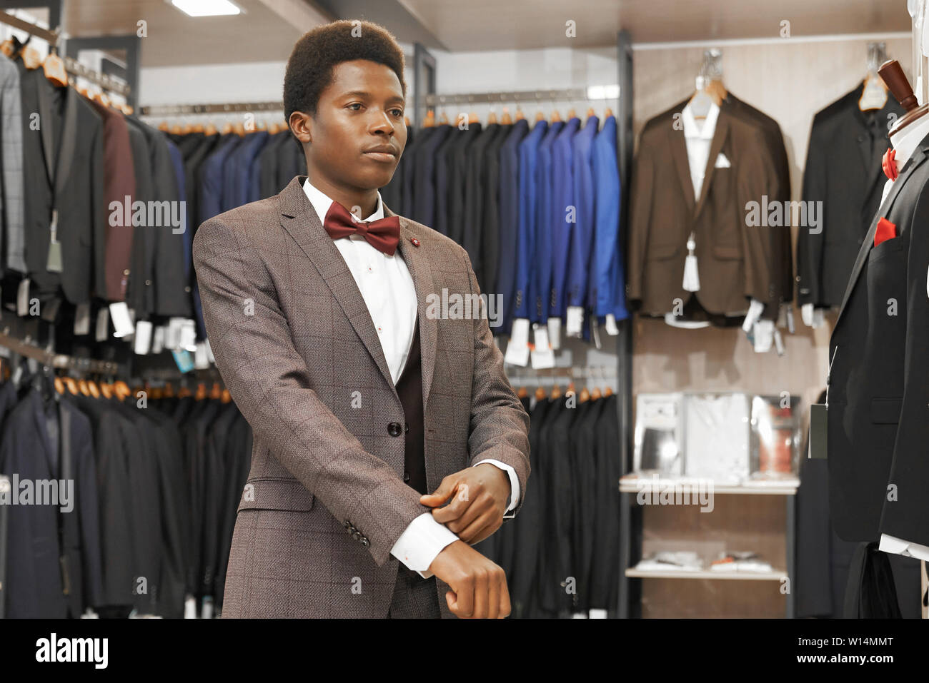 Young man choosing elegant suit in fashionable boutique. Customer ...