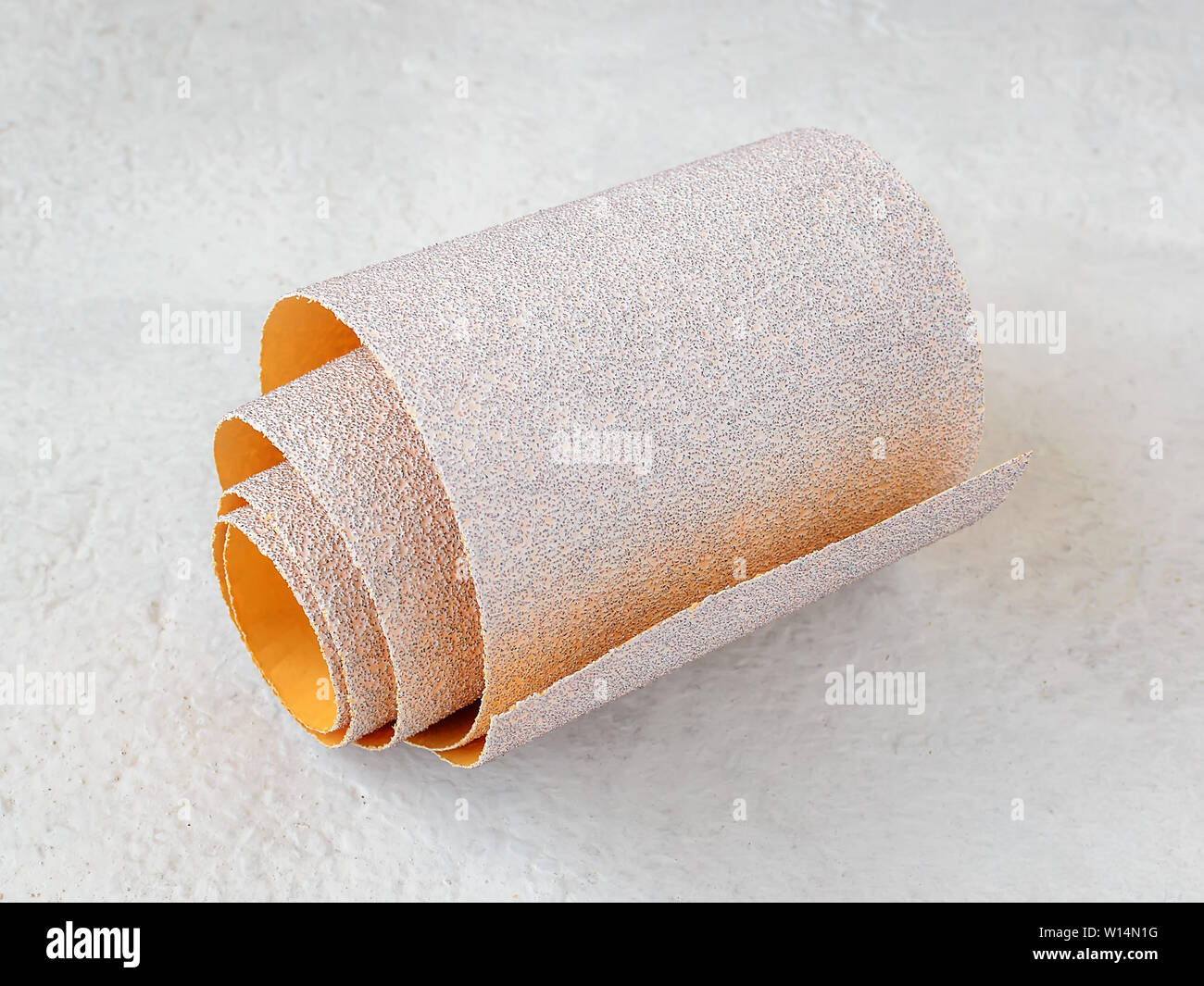 One small roll of extra coarse aluminum oxide sandpaper on a white ...