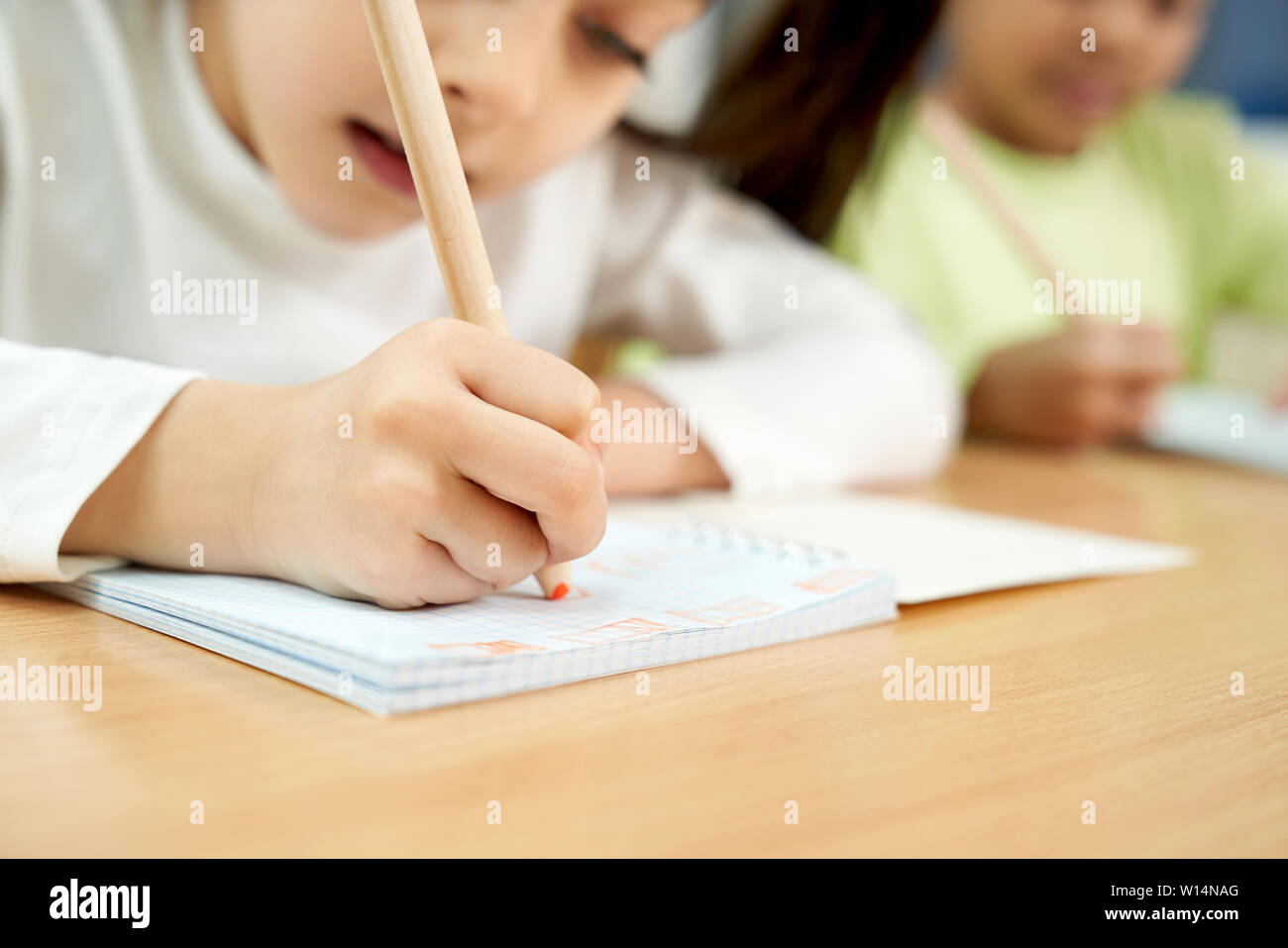 Selective focus of concentrated girl in process of writing in notebook ...