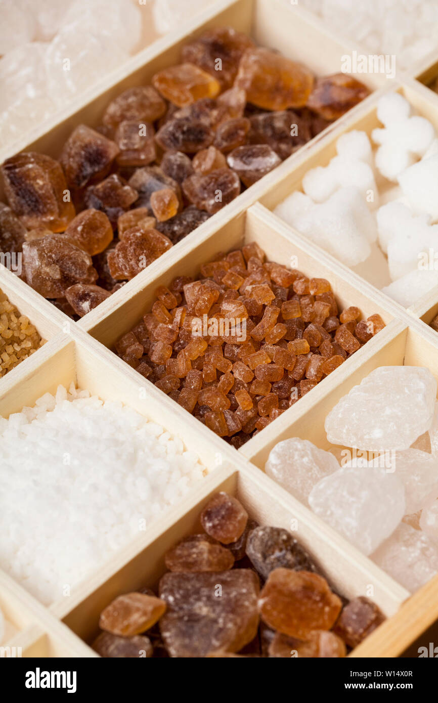 Various kinds of sugar in a wooden box. White refined, brown cane sugar ...