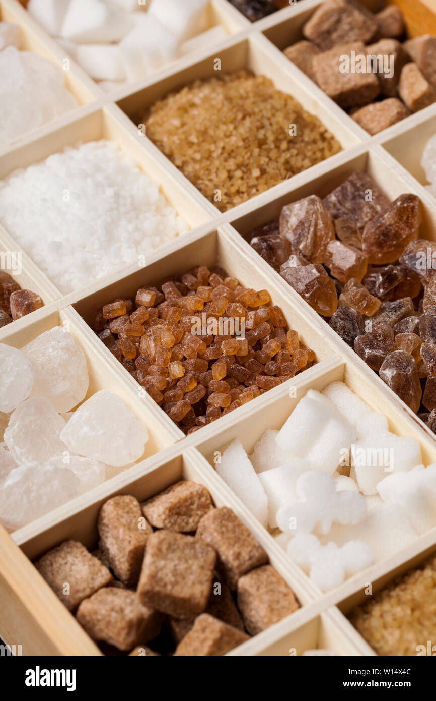 Various kinds of sugar in a wooden box. White refined, brown cane sugar ...