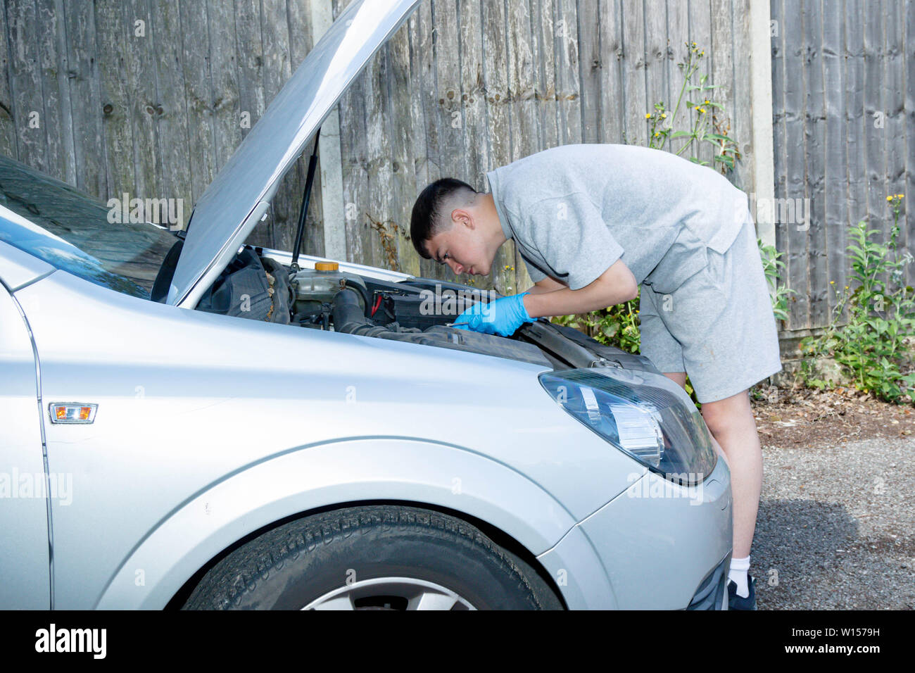 Teenage caucasian boy working on a car engine Stock Photo - Alamy