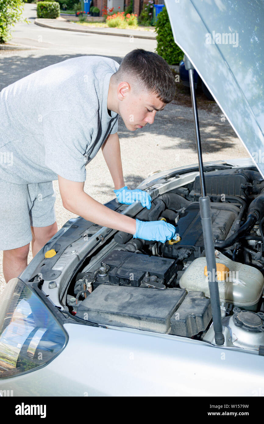 Teenage caucasian boy working on a car engine Stock Photo - Alamy