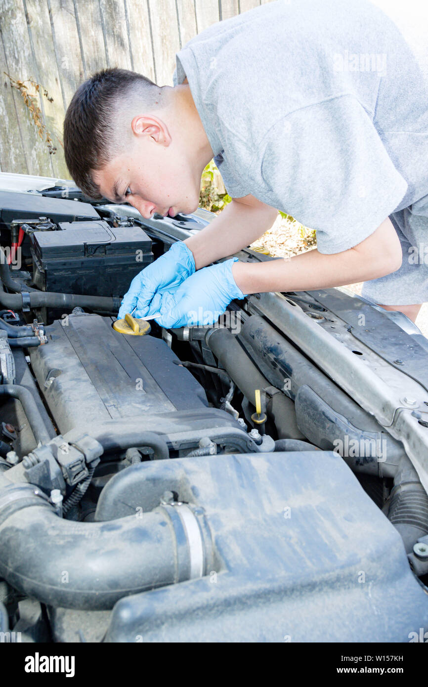 Teenage caucasian boy working on a car engine Stock Photo - Alamy