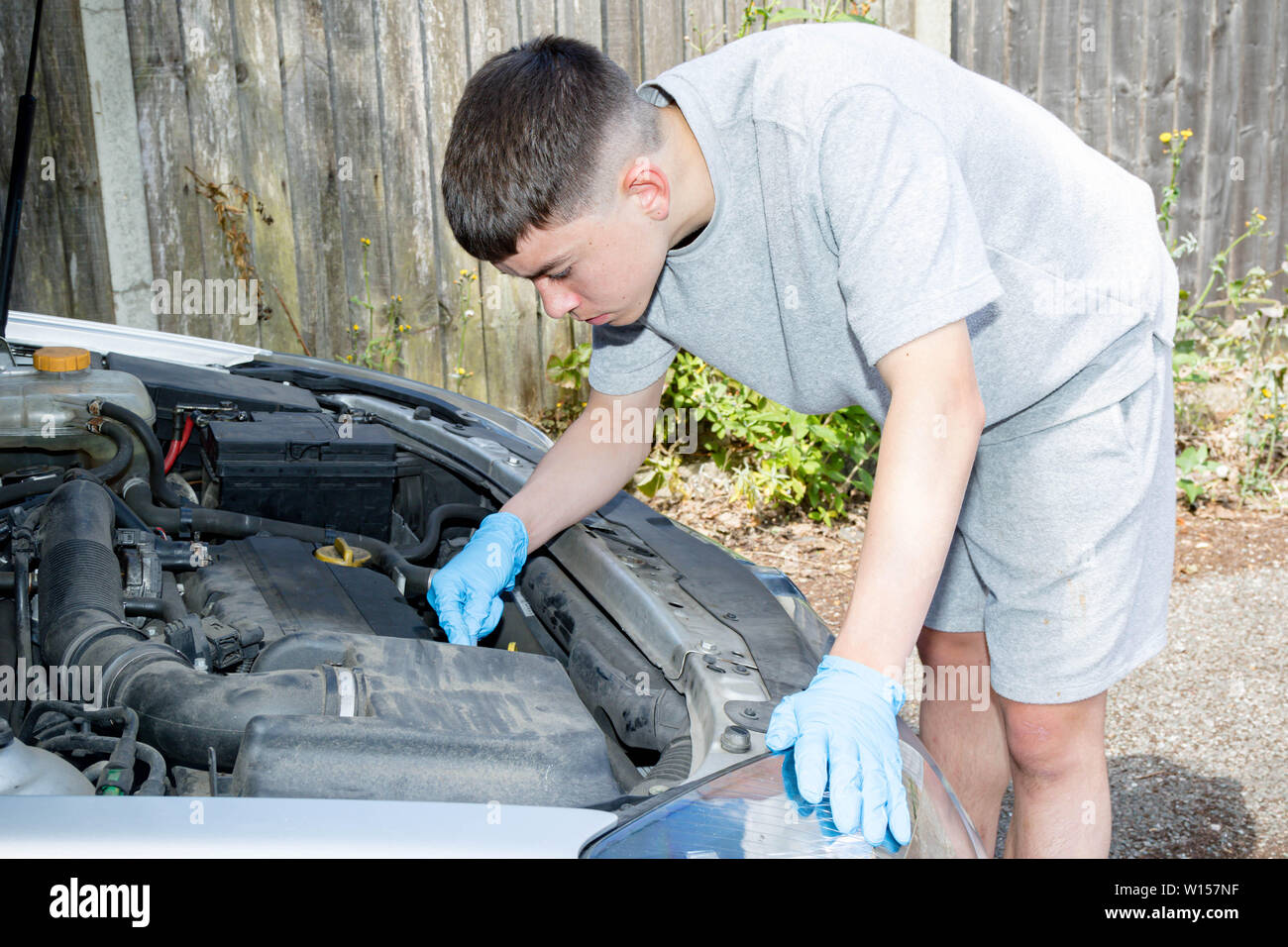 Teenage caucasian boy working on a car engine Stock Photo - Alamy