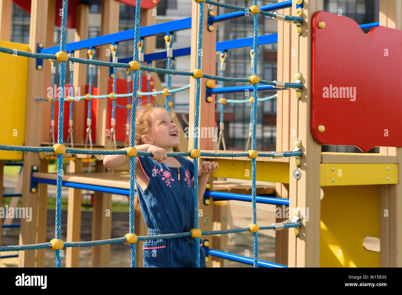 Teenage girl try to climbing on the rope wall. She is playing with the ...