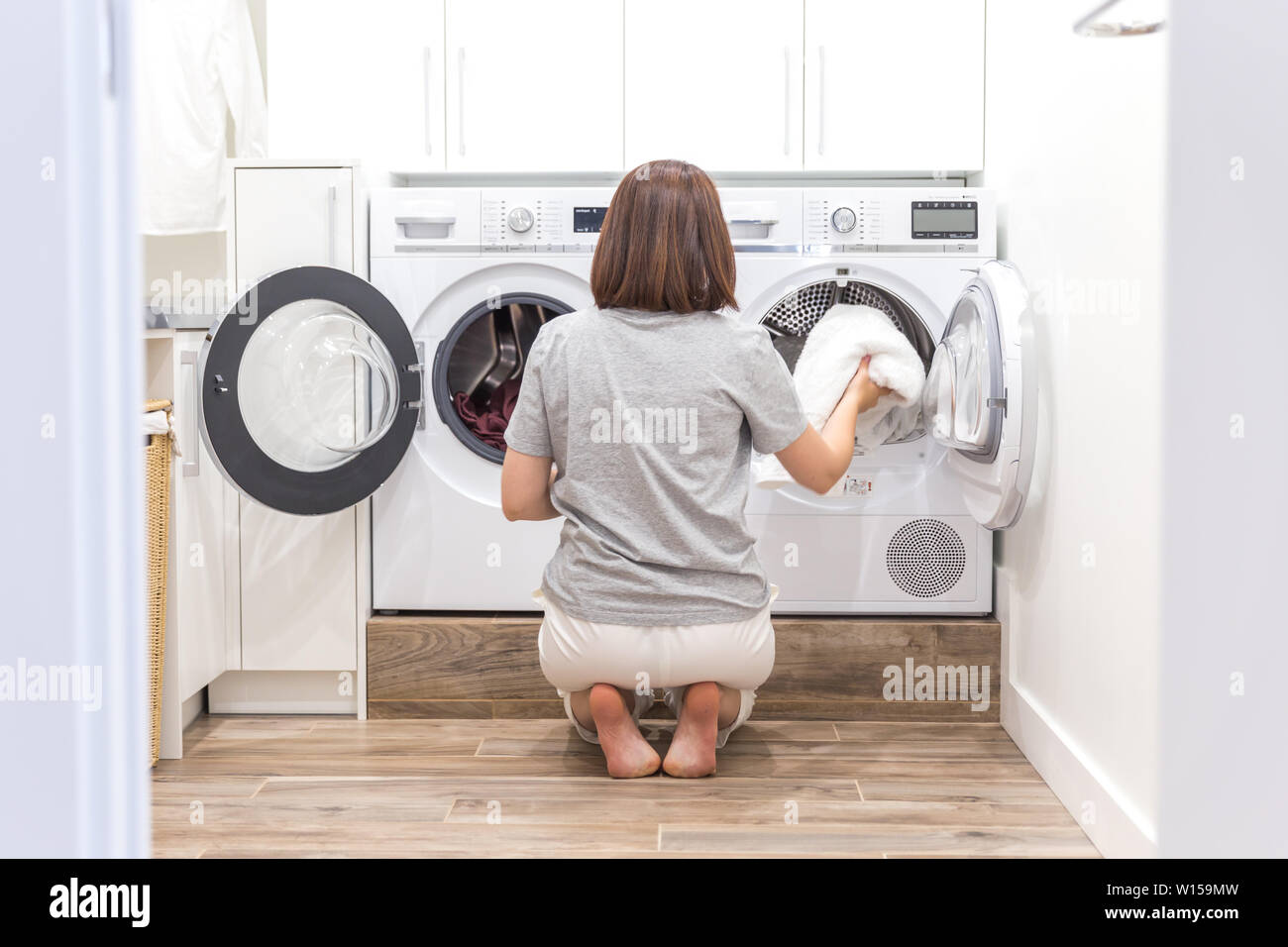 Woman putting clothes to washing machine for wash Stock Photo - Alamy