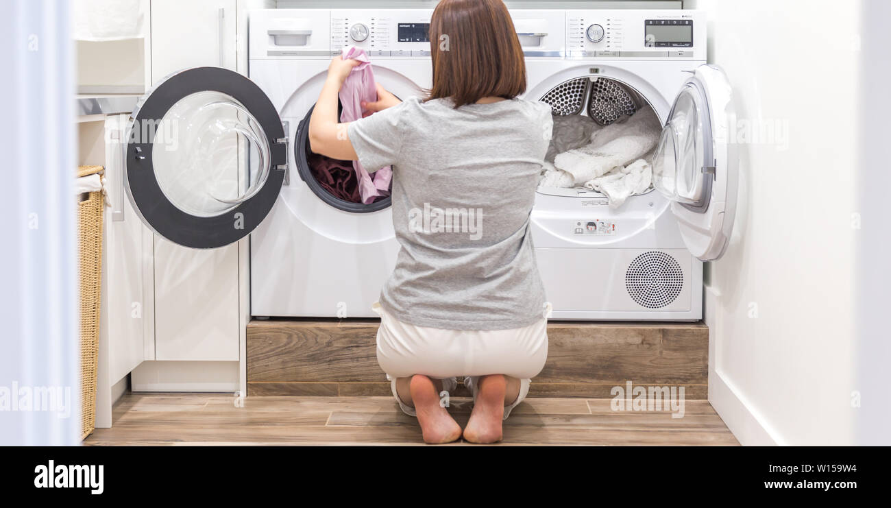 Woman putting clothes to washing machine for wash Stock Photo - Alamy