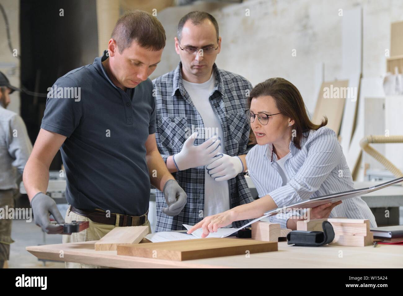 Team of carpenters workshop workers discussing a furniture project with ...
