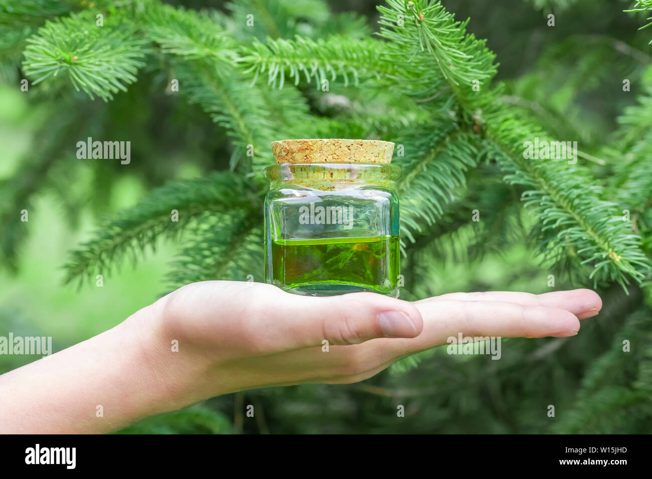 A glass jar with a wooden lid half filled with green-yellow nectar oil ...