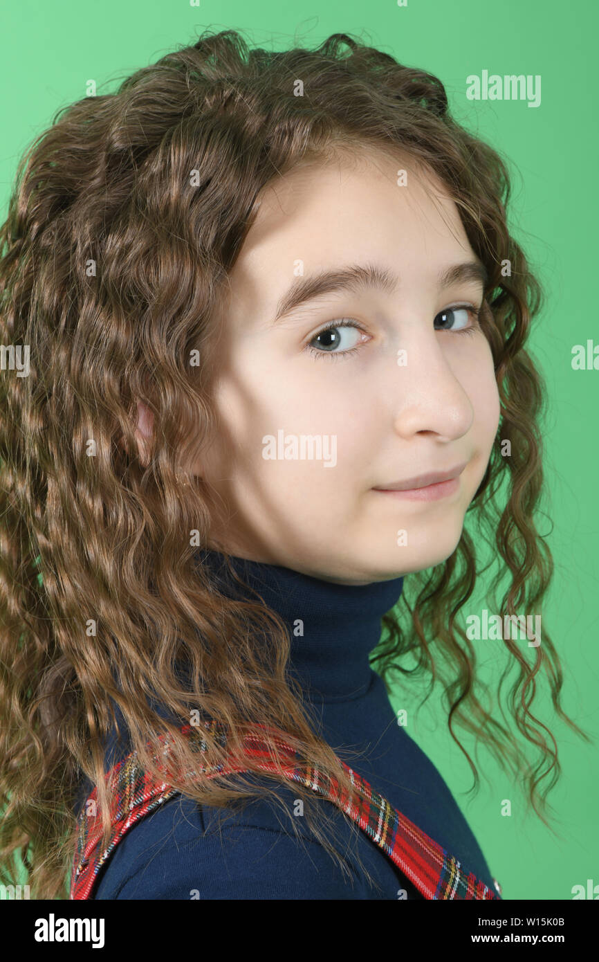 Portrait of adorable smiling schoolgirl with curl hair standing ...