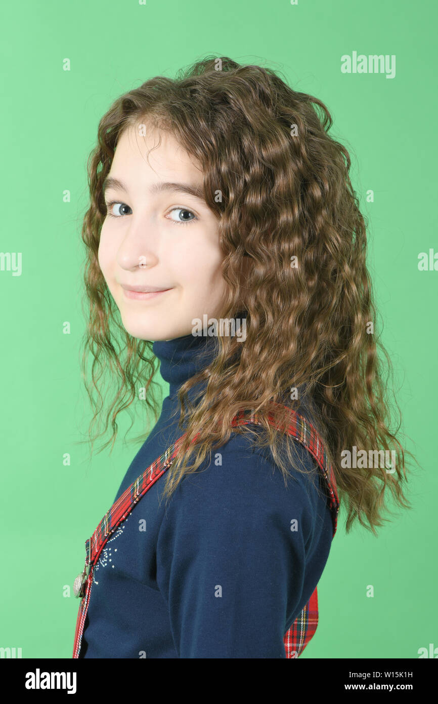 Portrait of adorable smiling schoolgirl with curl hair standing ...