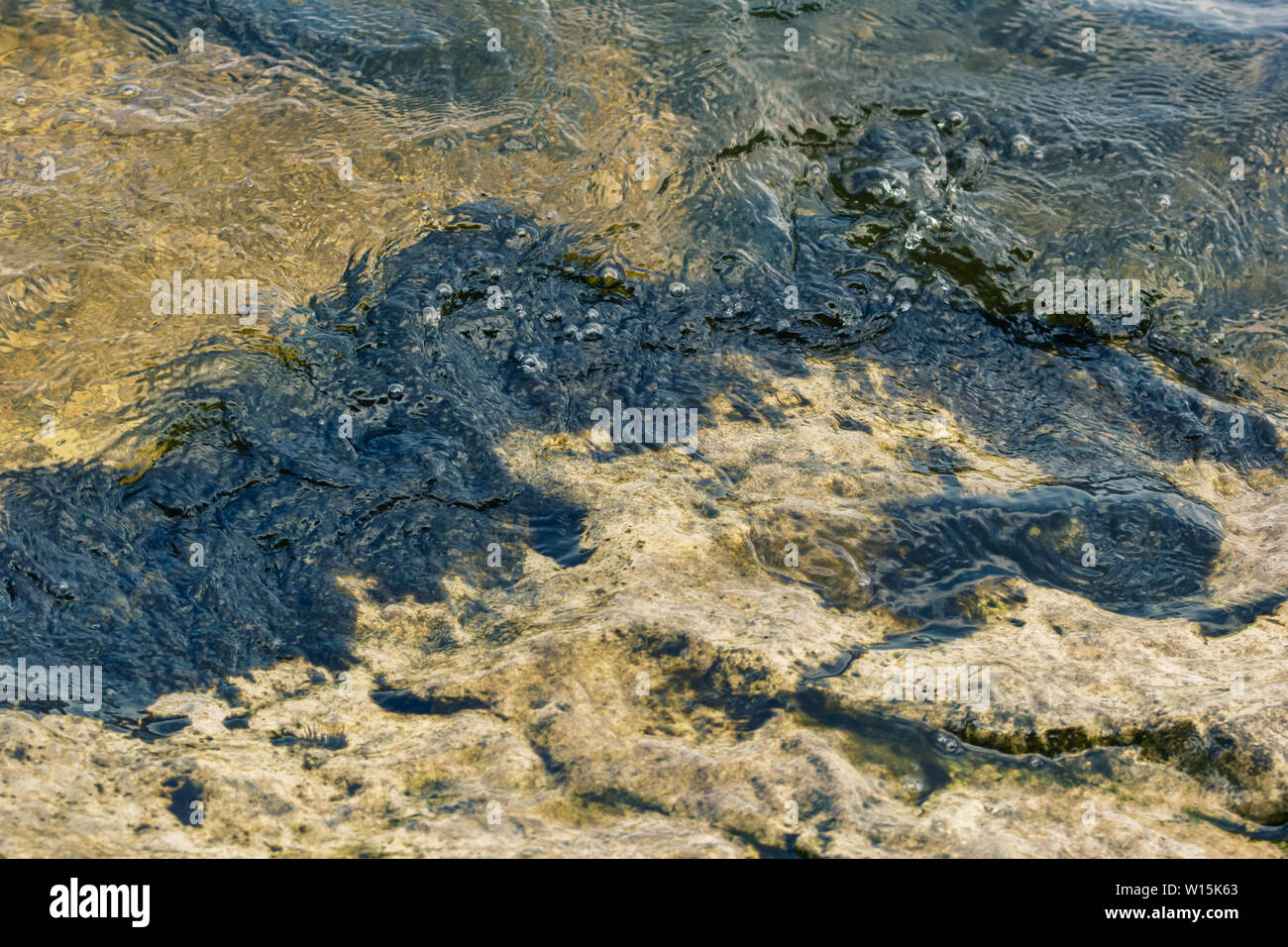 Natural liquid texture. River wave runs on the rocky shore Stock Photo ...