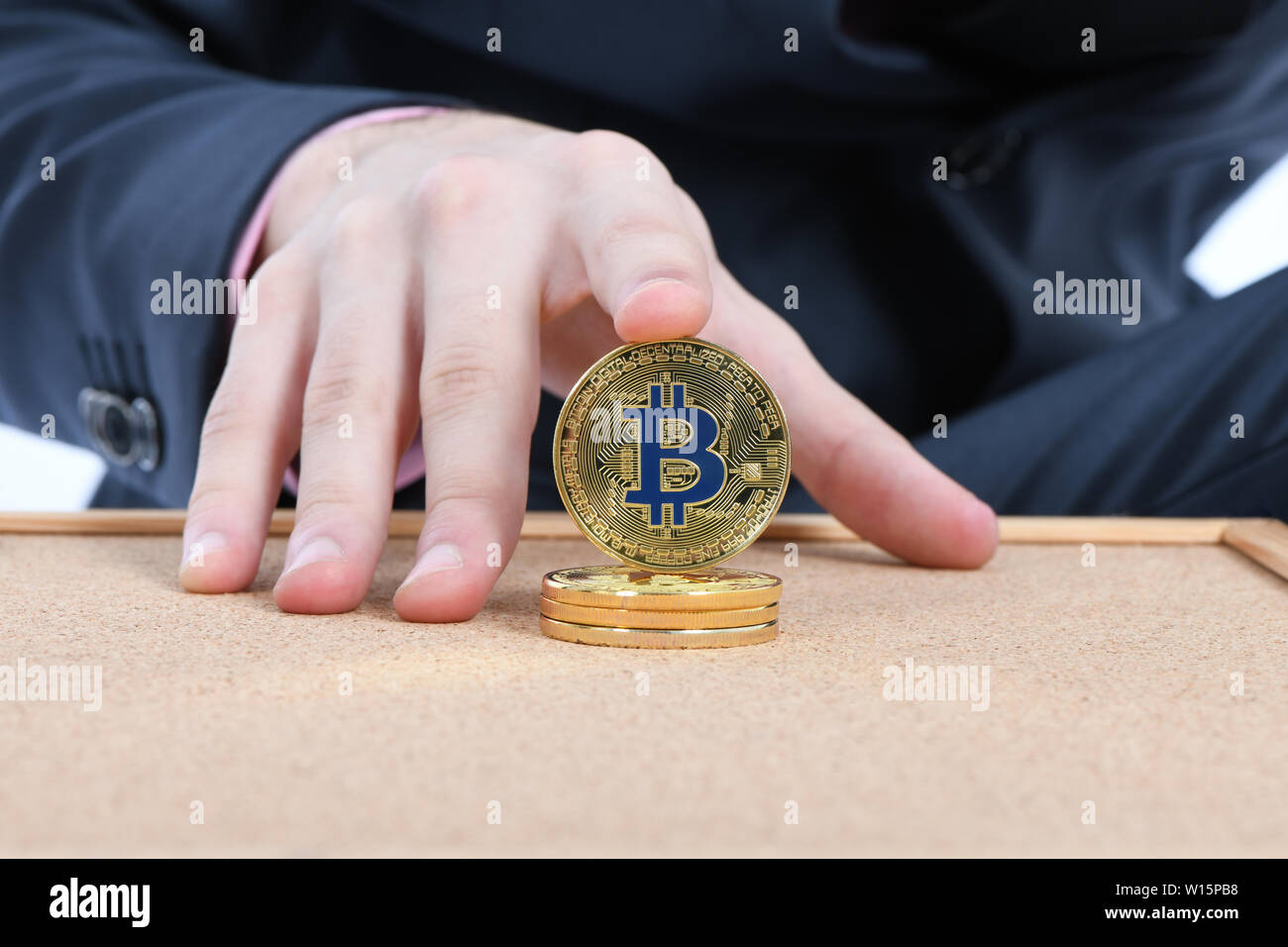 Man's hand holding golden Bitcoin on brown textured cork background ...