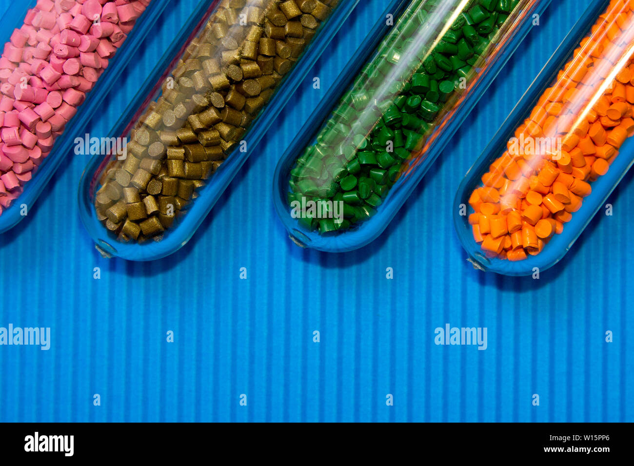 Plastic pellets .Polymeric dye in test tubes on blue corrugated ...