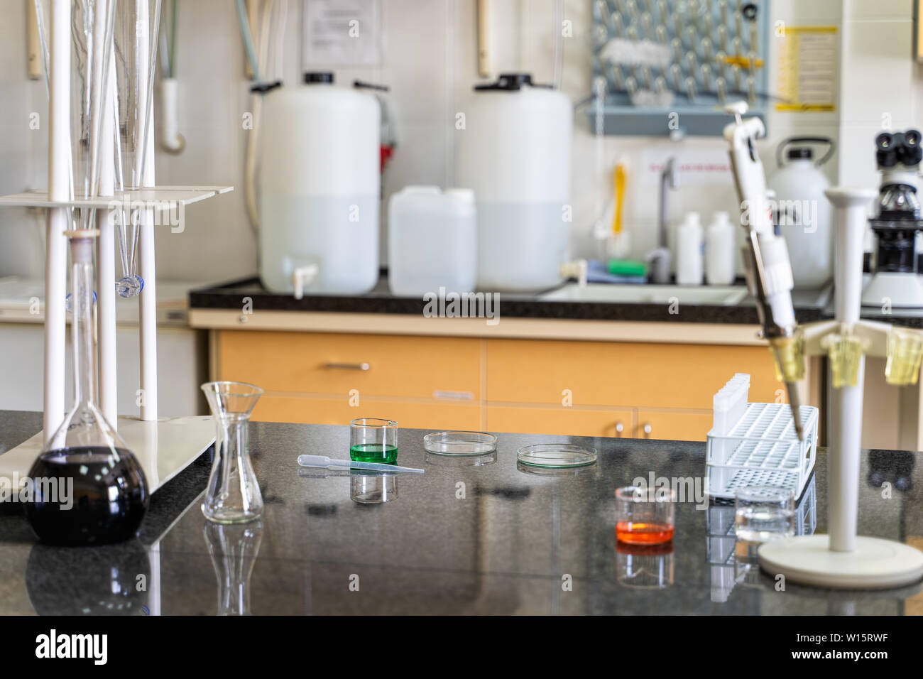 Pipette and colourful chemical liquid solutions in flasks on laboratory ...