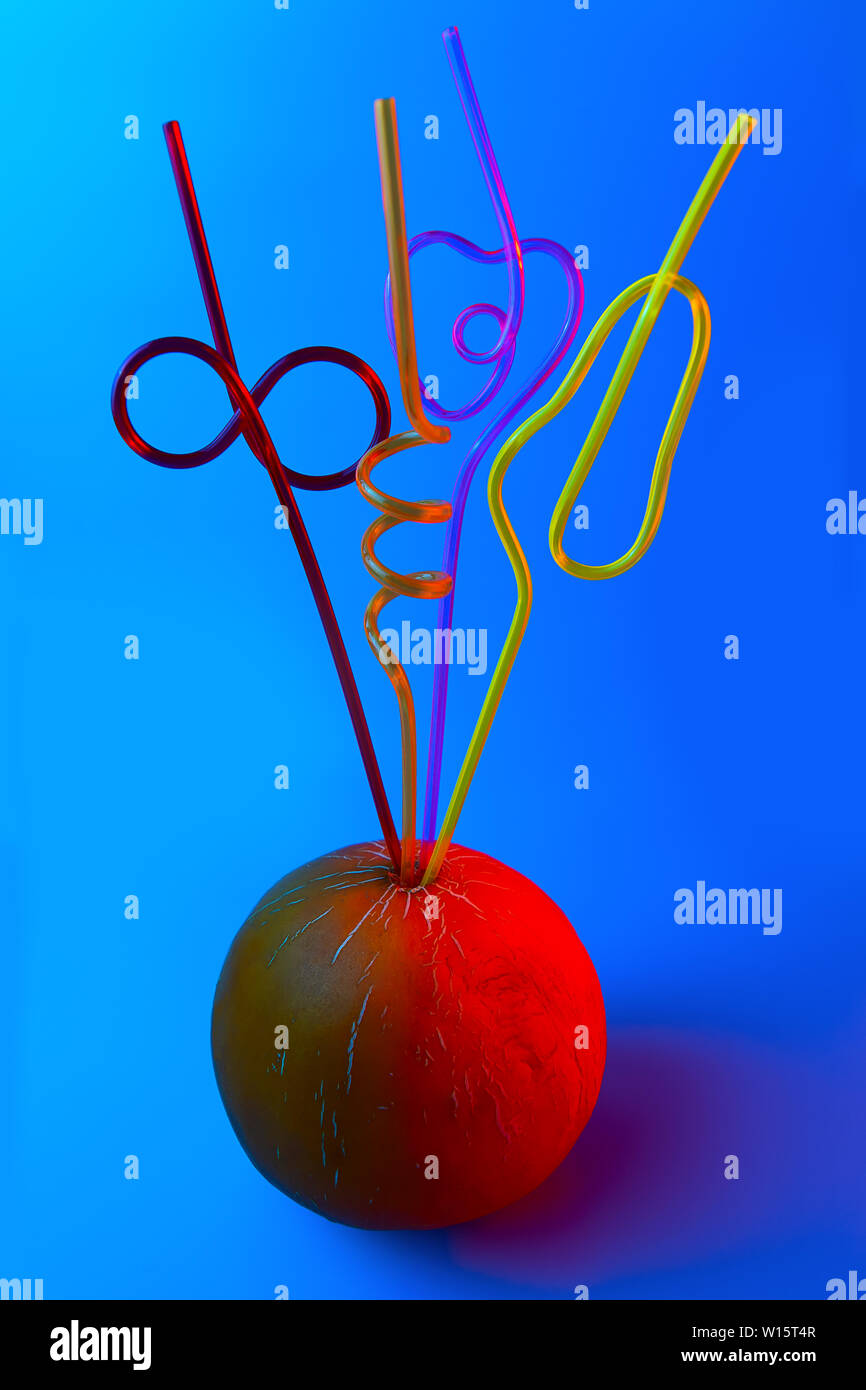 bright colored cocktail tubes stuck in a melon on a blue background ...